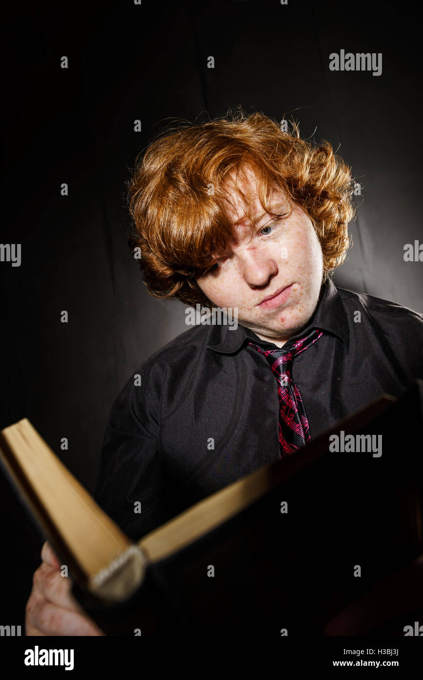Freckled red-haired teenage boy reading book, education concept ...