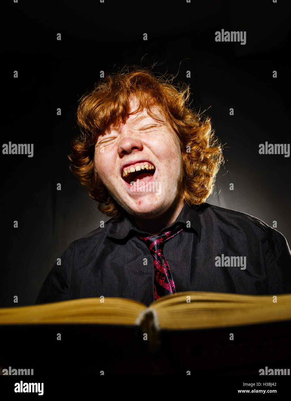 Freckled red-haired teenage boy reading book, education concept ...