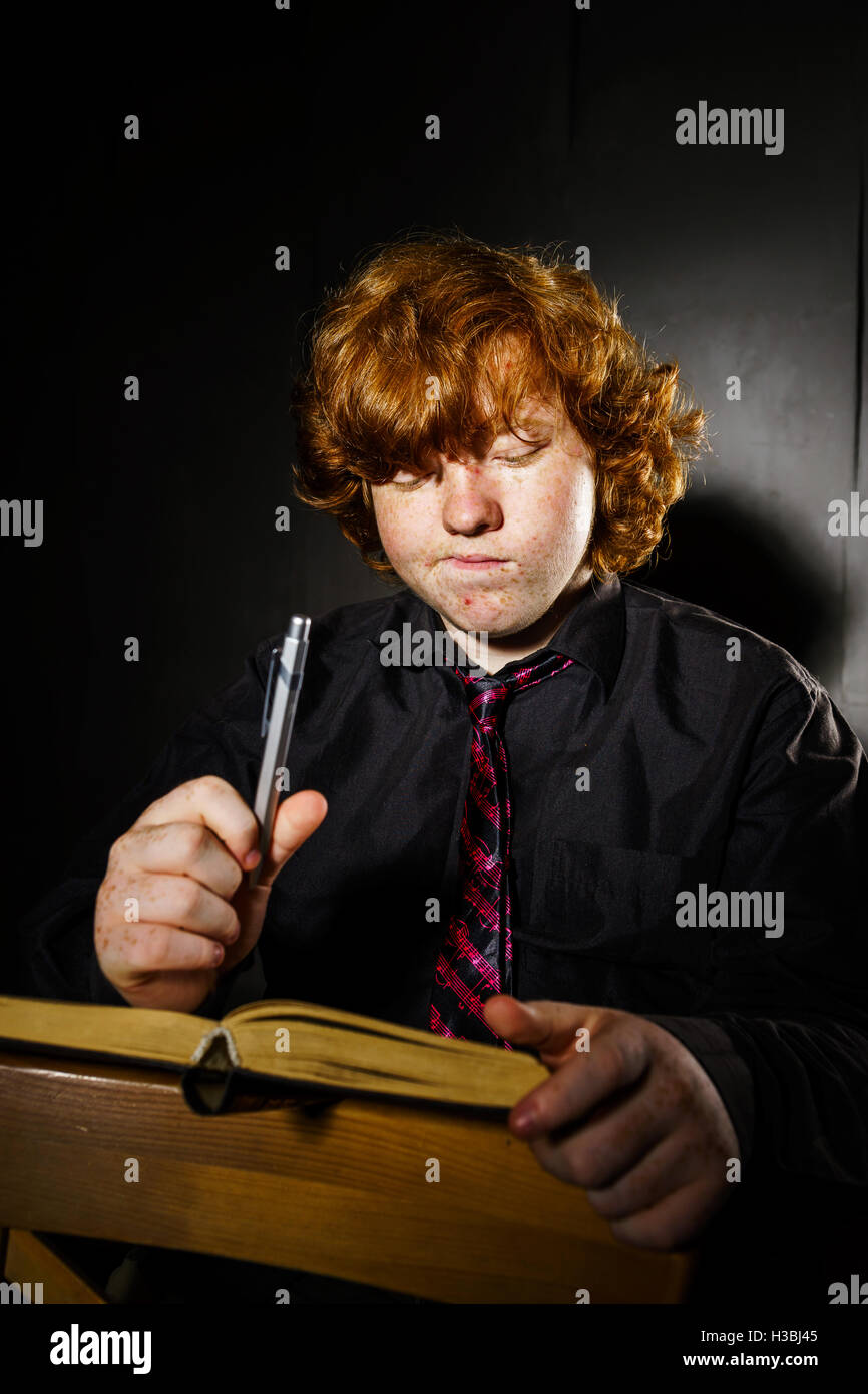 Freckled red-haired teenage boy reading book, education concept ...