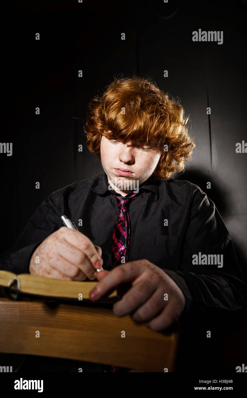 Freckled red-haired teenage boy reading book, education concept ...