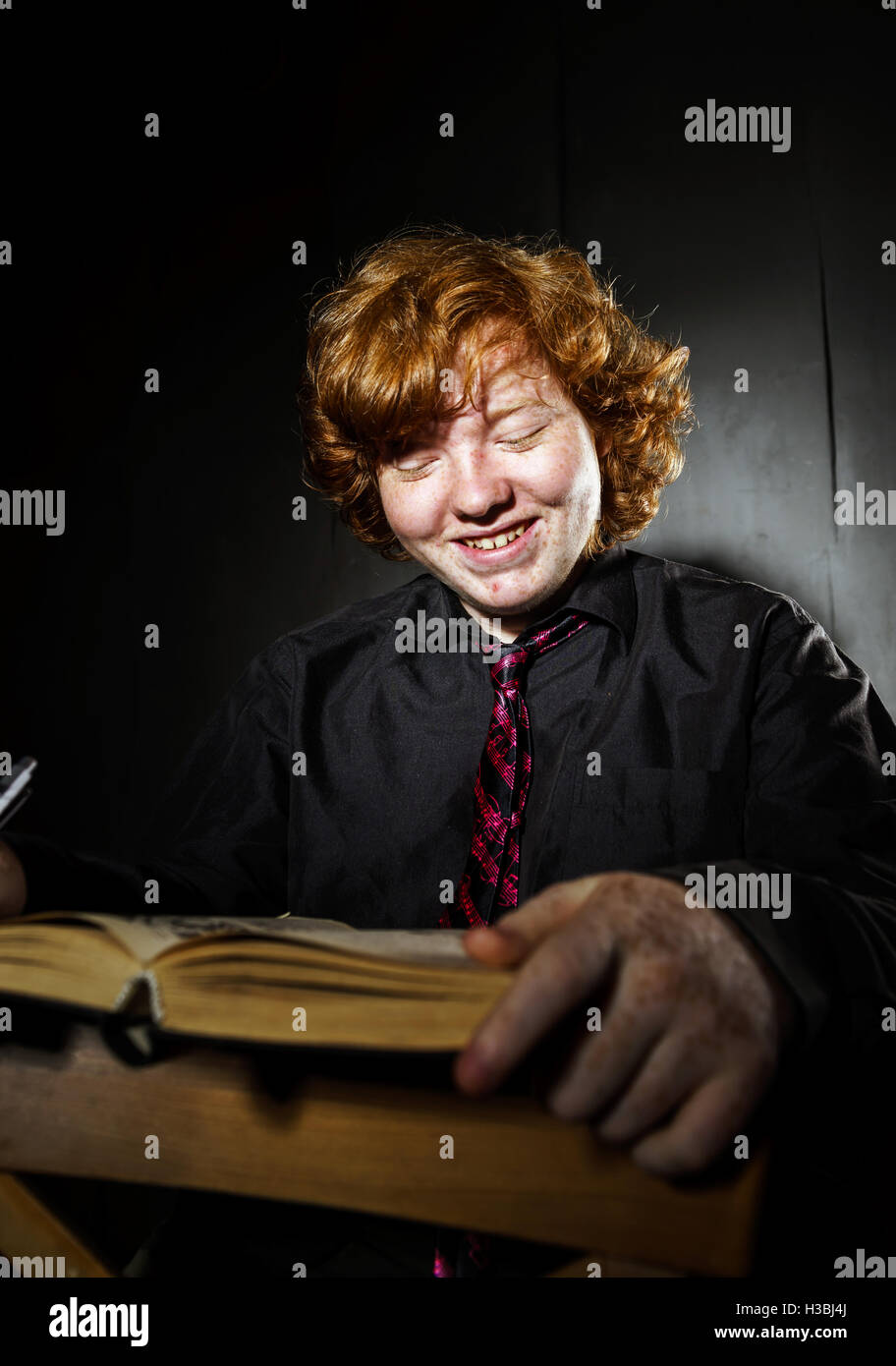 Freckled red-haired teenage boy reading book, education concept ...