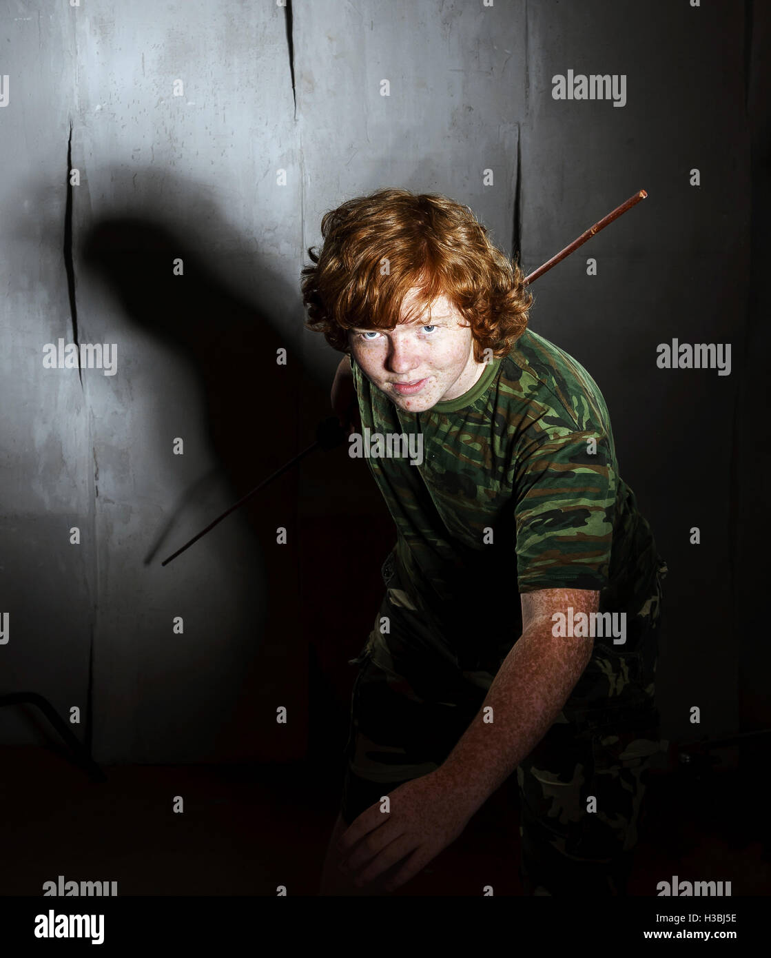 Red-haired freckled fat boy posing like a soldier, studio shooting ...