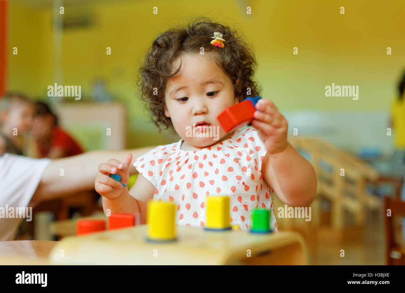 kazakh curly girl playing in kids development center Stock Photo - Alamy