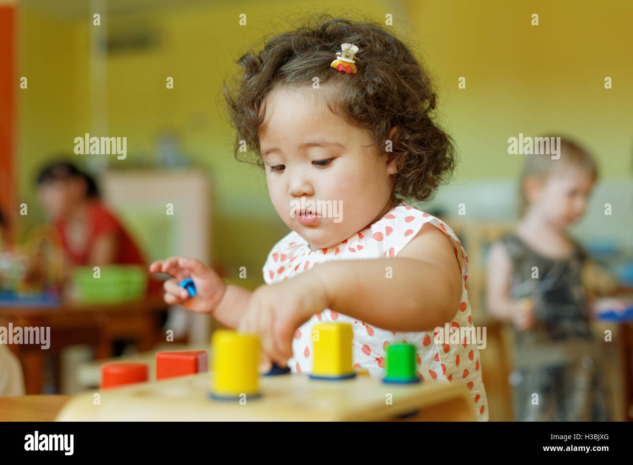 kazakh curly girl playing in kids development center Stock Photo - Alamy