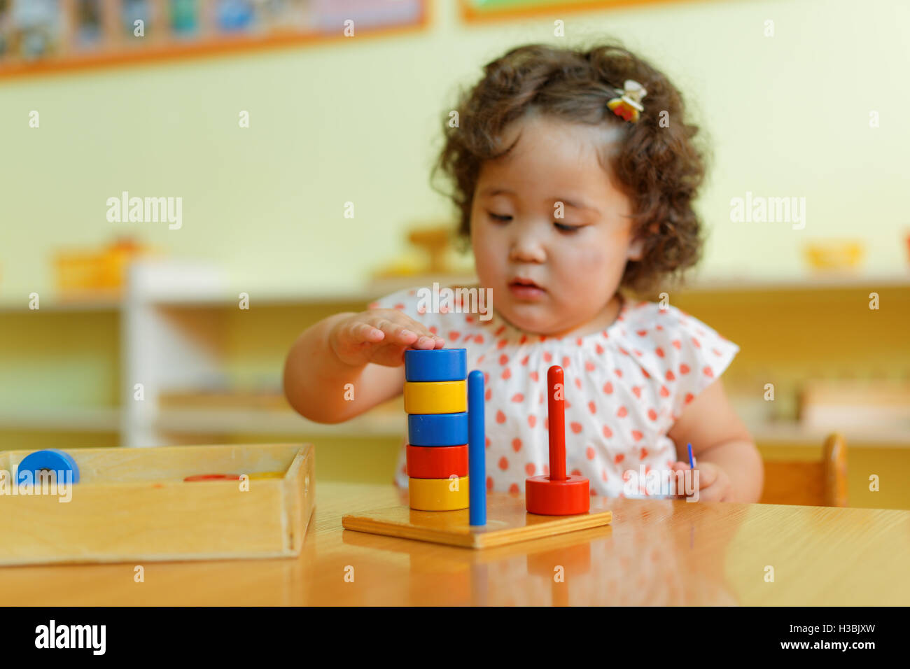 kazakh curly girl playing in kids development center Stock Photo - Alamy