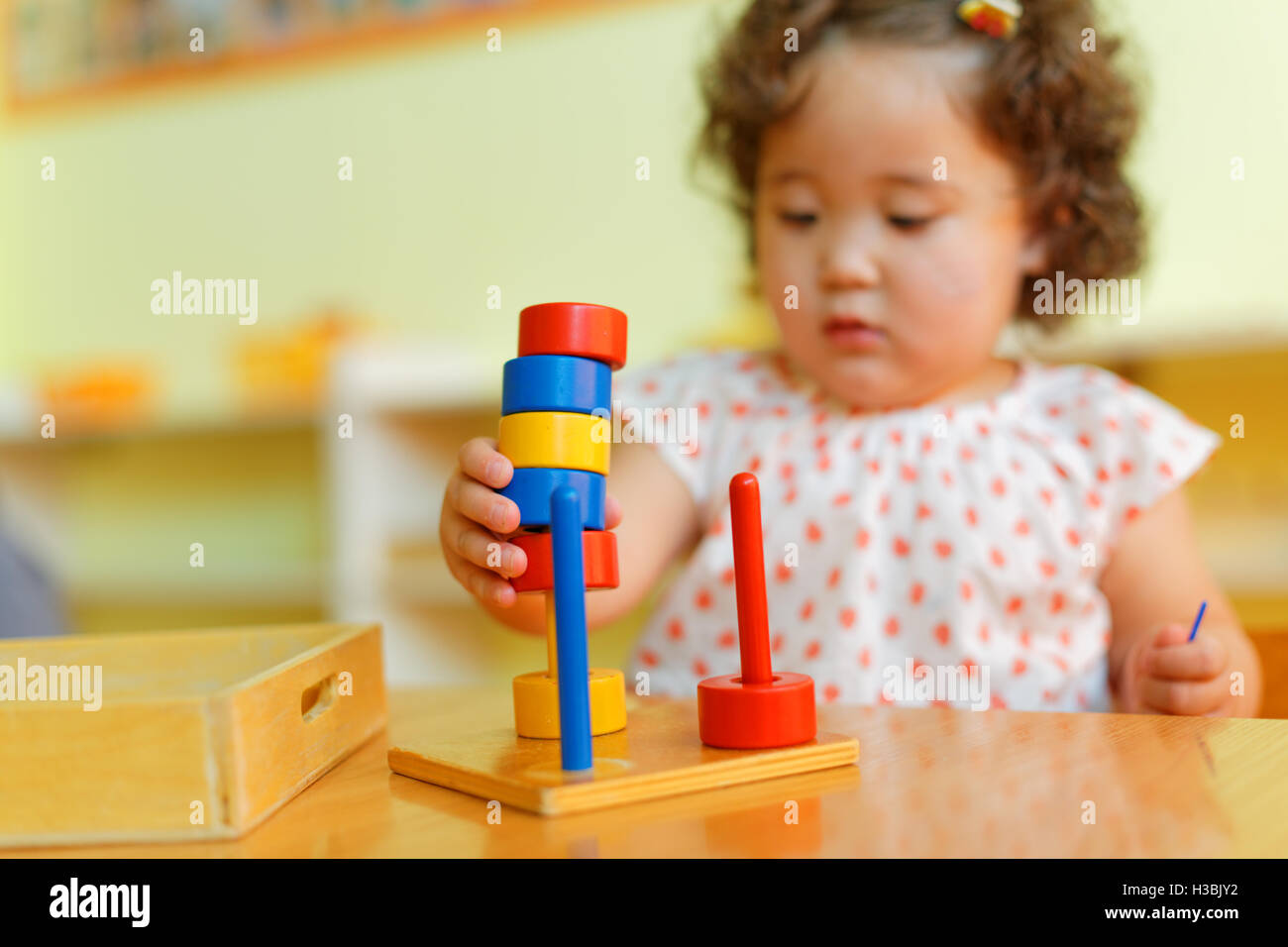 kazakh curly girl playing in kids development center Stock Photo - Alamy