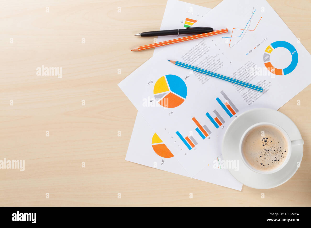 Office desk workplace with coffee cup and charts on wooden table. Top ...