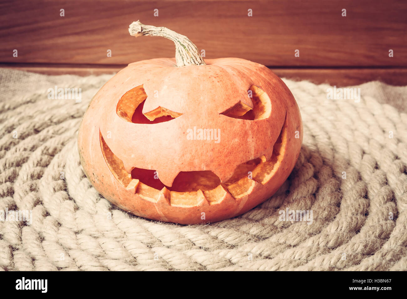 Halloween pumpkin on coiled rope with wooden background Stock Photo - Alamy