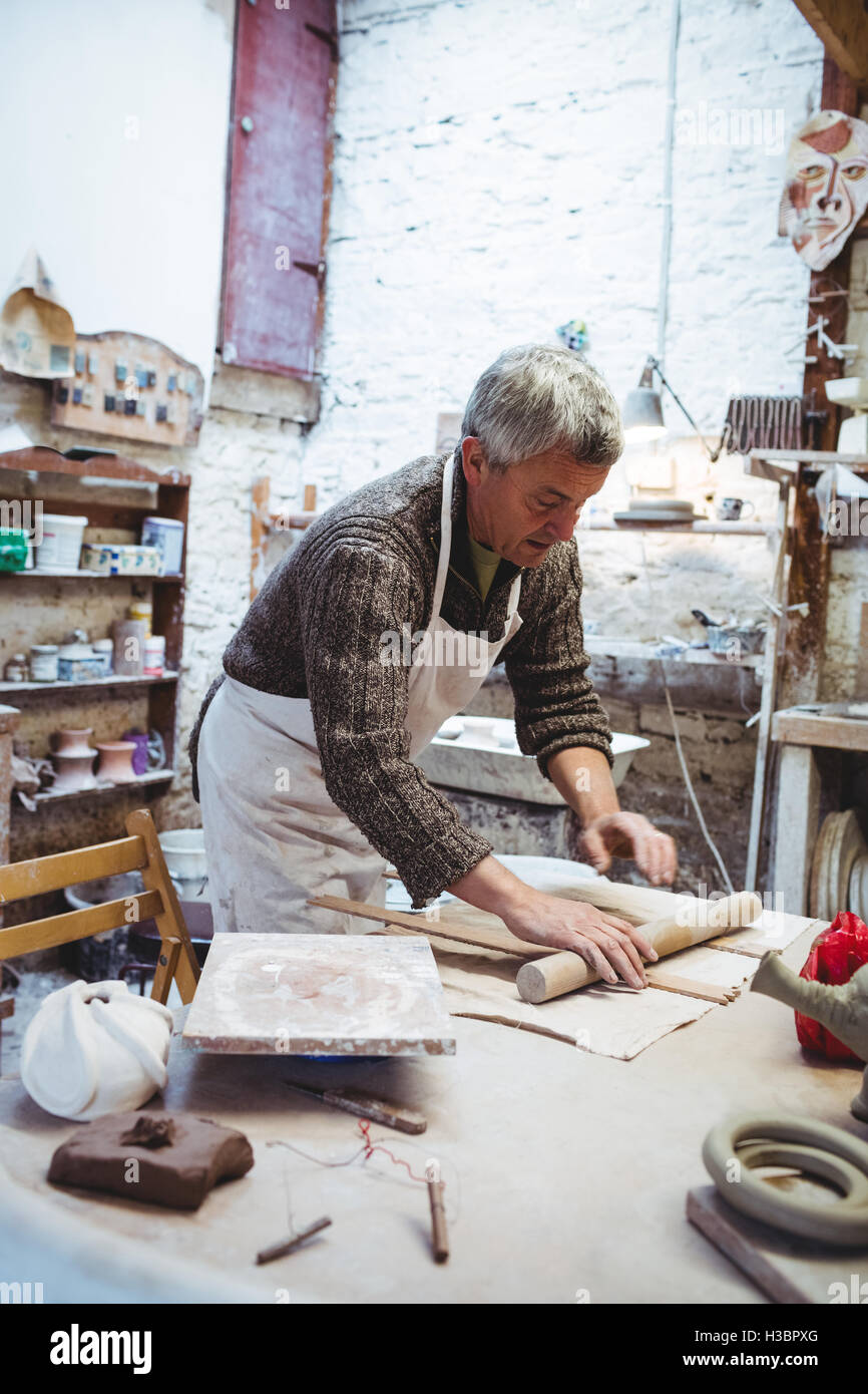 Mature potter bending while working at table Stock Photo - Alamy