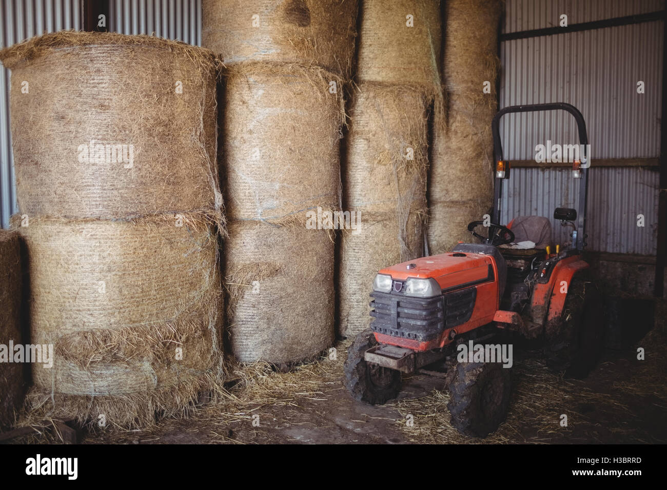 Hay bales and tractor in barn Stock Photo - Alamy