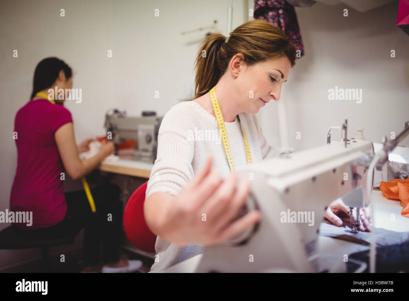 Female dressmaker sewing in the studio Stock Photo - Alamy