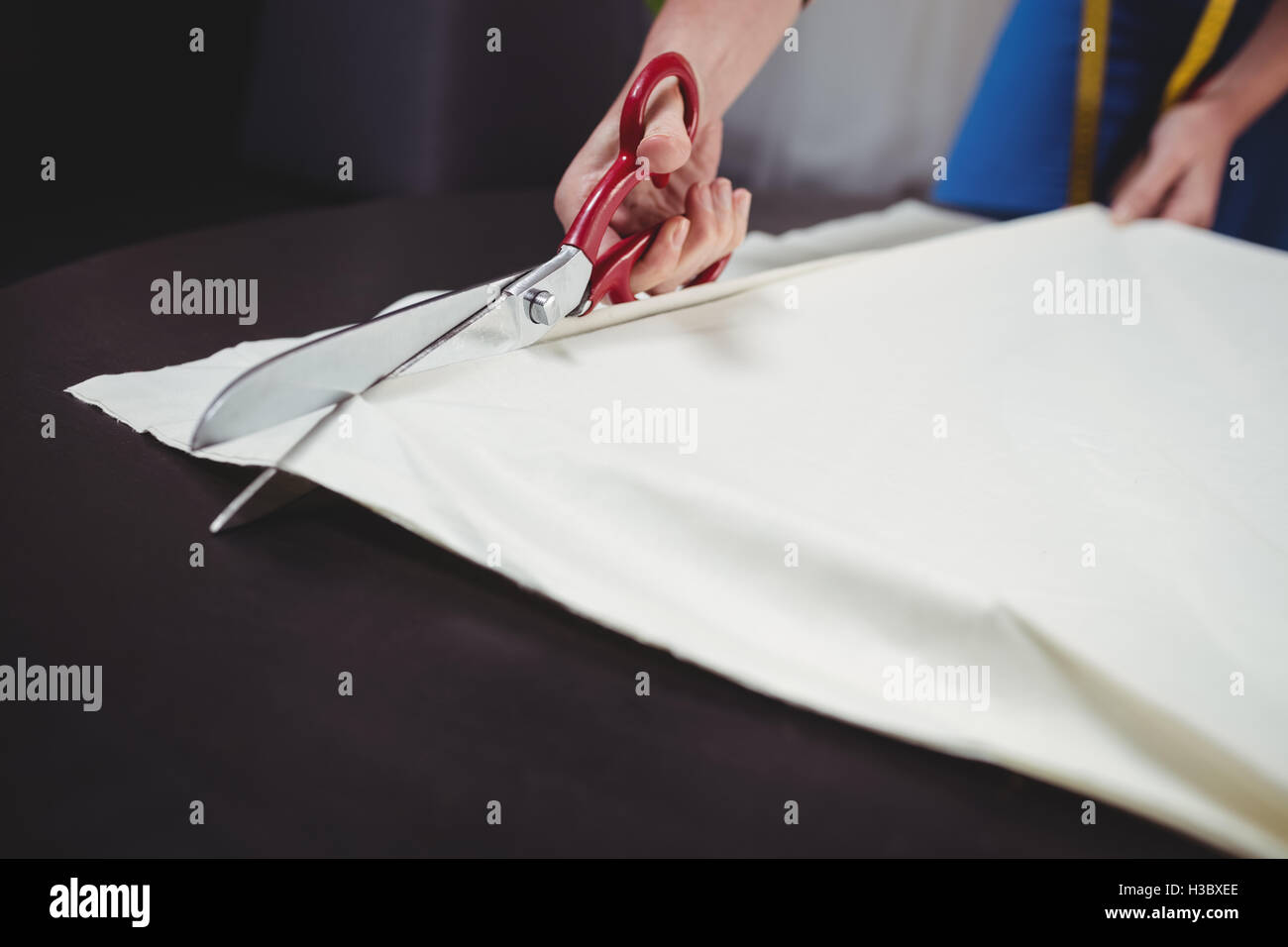 Female fashion designer cutting a white fabric Stock Photo - Alamy