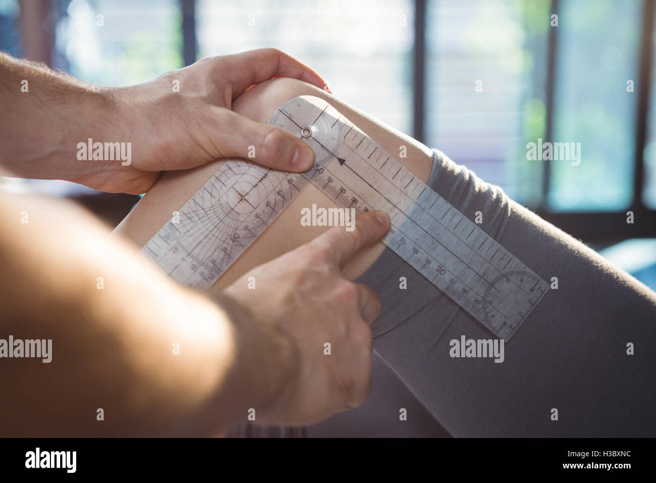Male therapist measuring female patient knee with goniometer Stock ...