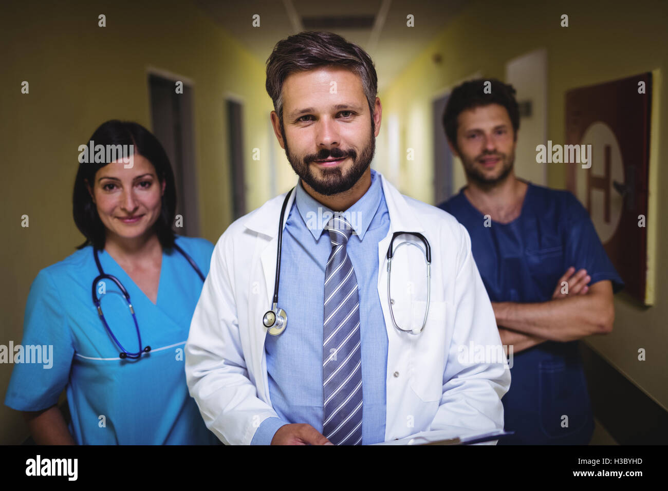 Portrait of doctor standing with nurse and ward boy in corridor Stock ...