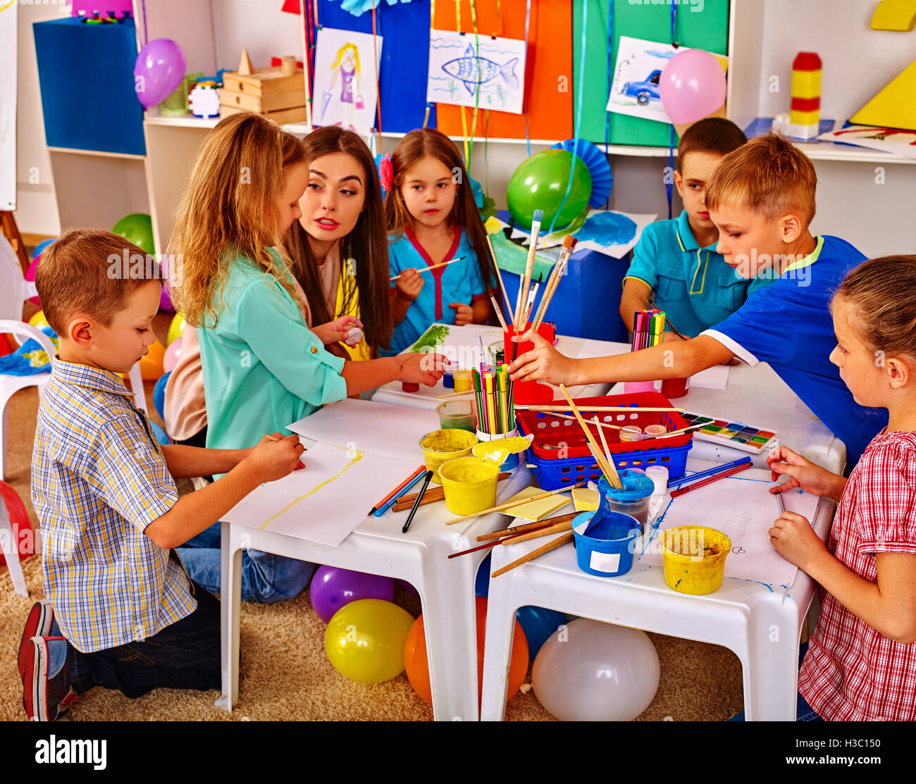 Children with teacher make overall project painting paper in ...