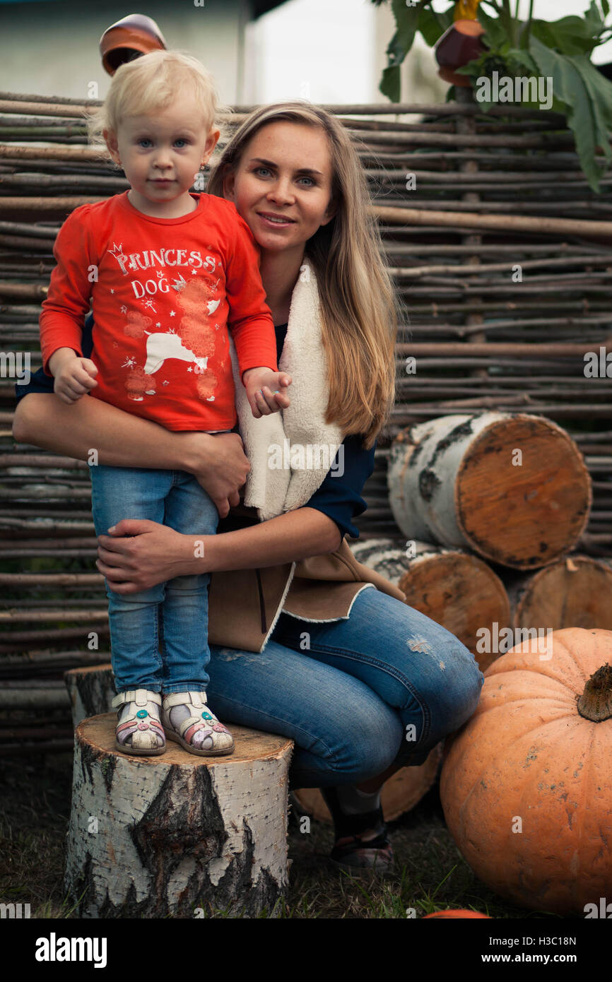 mother and daughter on a background of pumpkins. stump Stock Photo - Alamy
