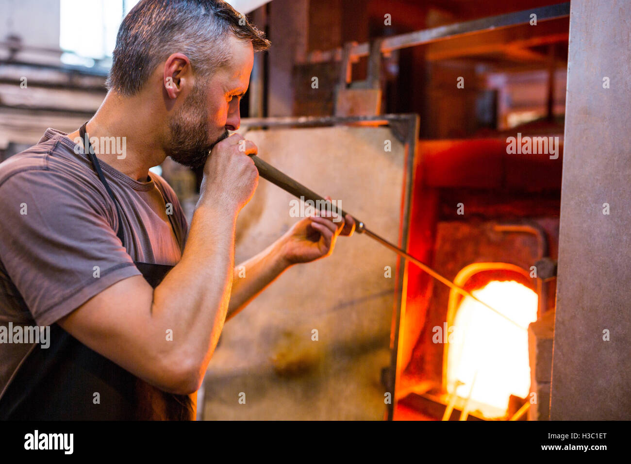 Glassblower heating a glass in furnace Stock Photo - Alamy