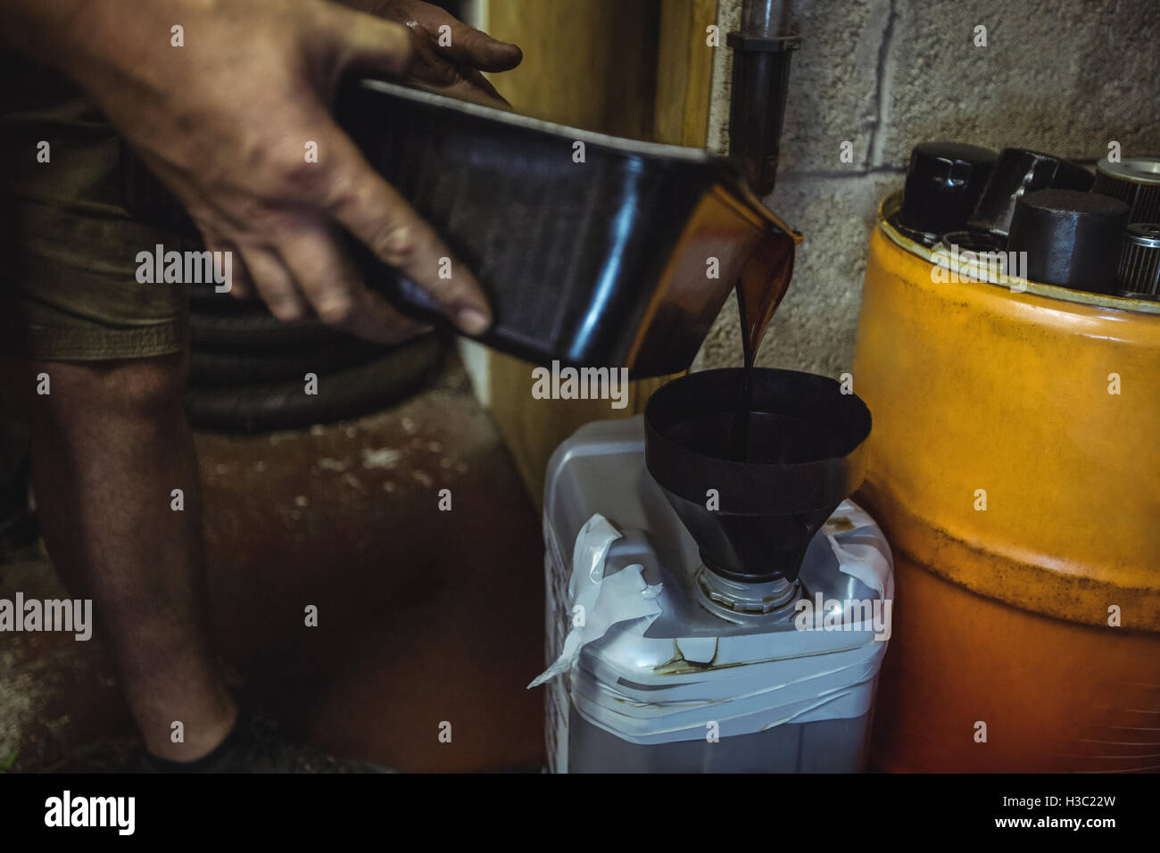 Mechanic pouring oil into can Stock Photo - Alamy