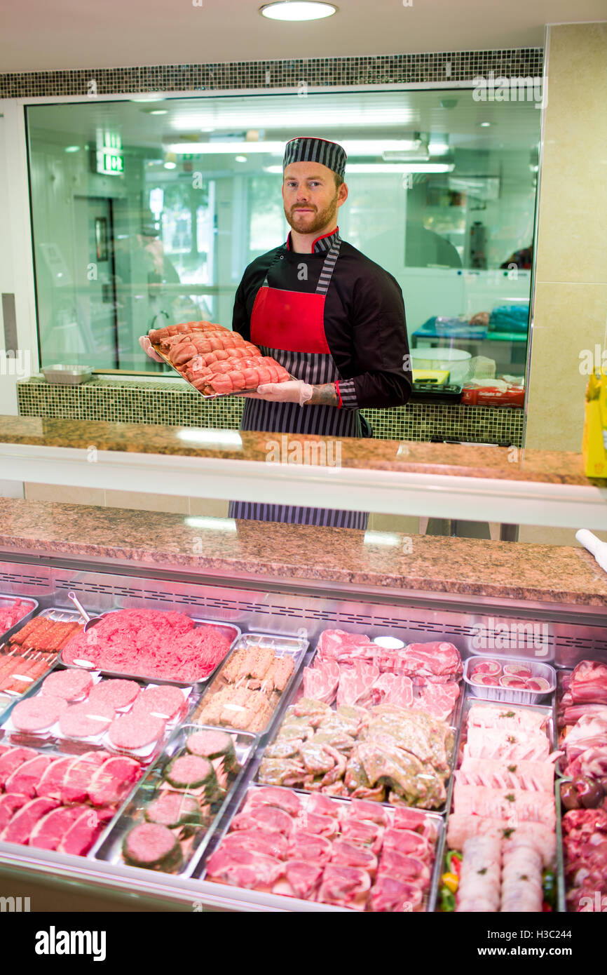 Butcher standing at meat counter Stock Photo - Alamy