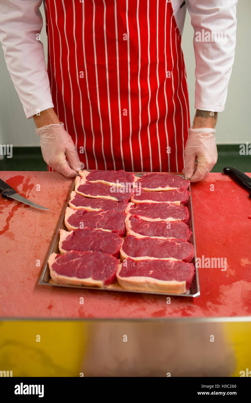 Mid section of butcher standing with a tray of steaks Stock Photo - Alamy