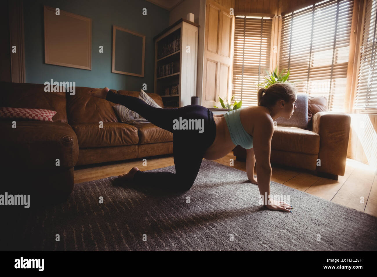 Pregnant Woman Performing Stretching Exercise In Living Room Stock