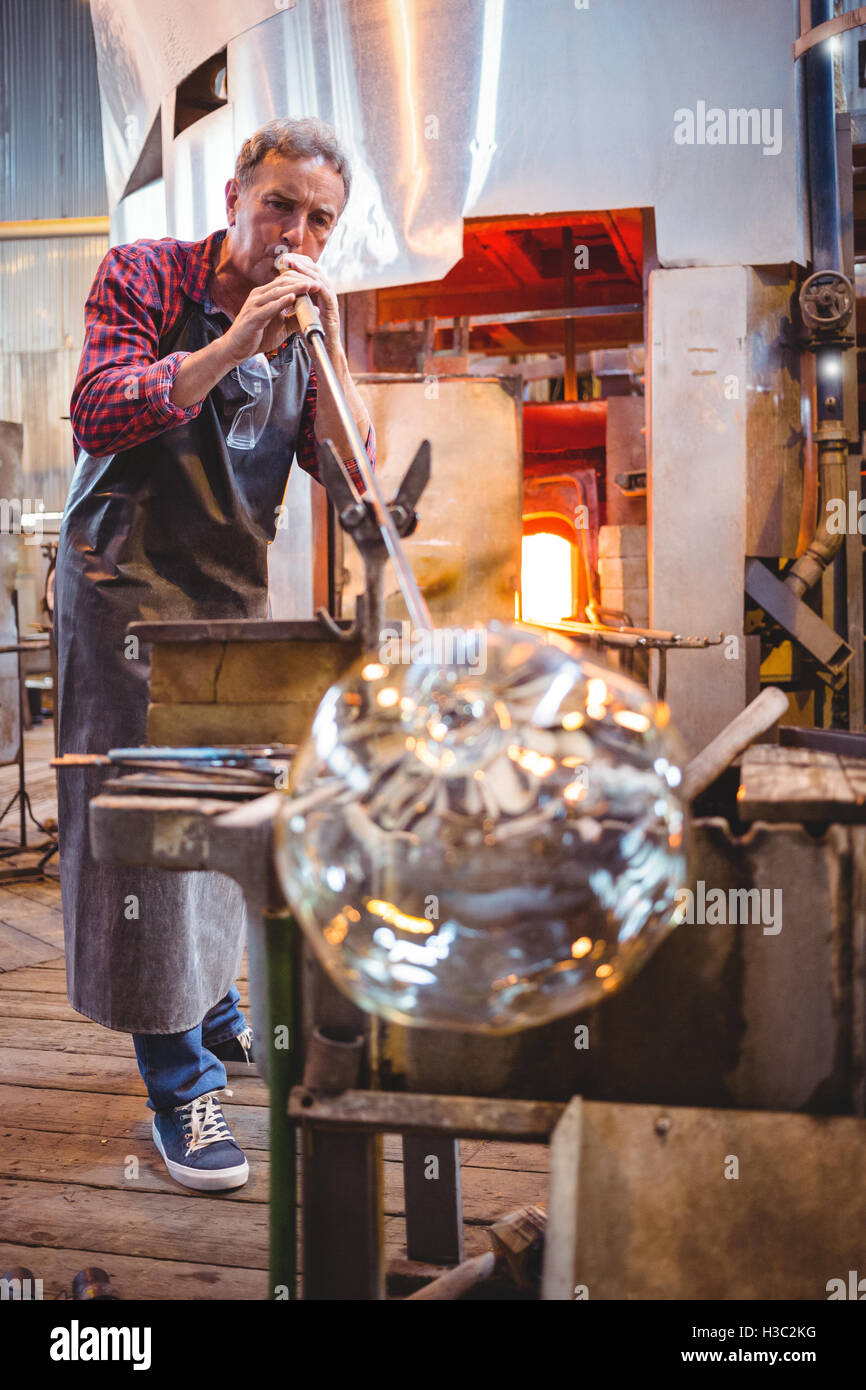 Glassblower shaping a glass on the blowpipe Stock Photo - Alamy