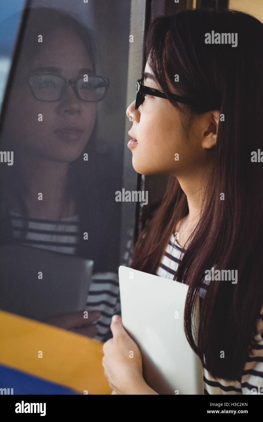 Young woman looking through window Stock Photo - Alamy