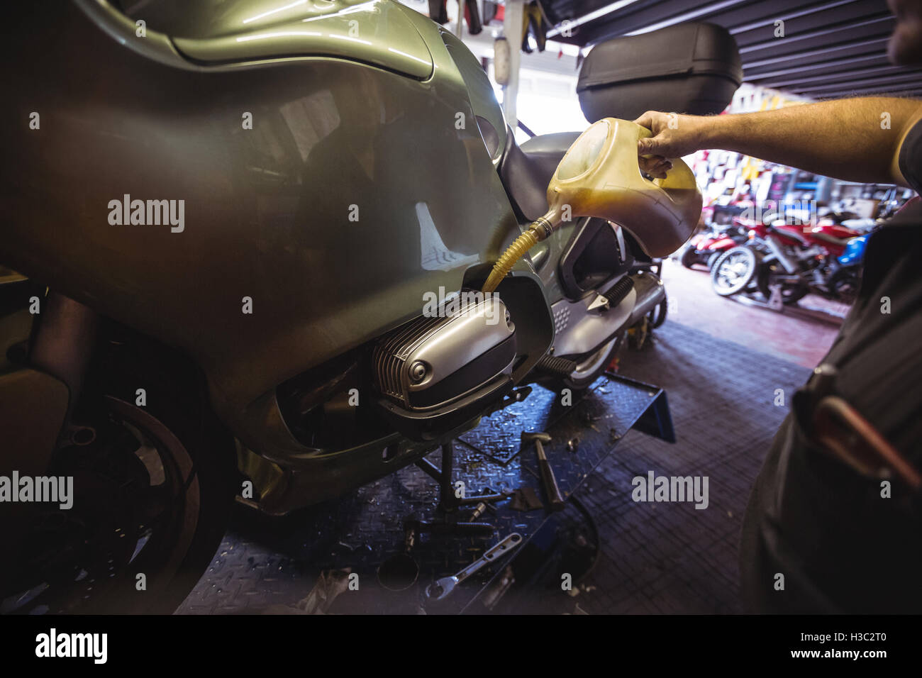 Mechanic pouring oil into oil tank Stock Photo - Alamy