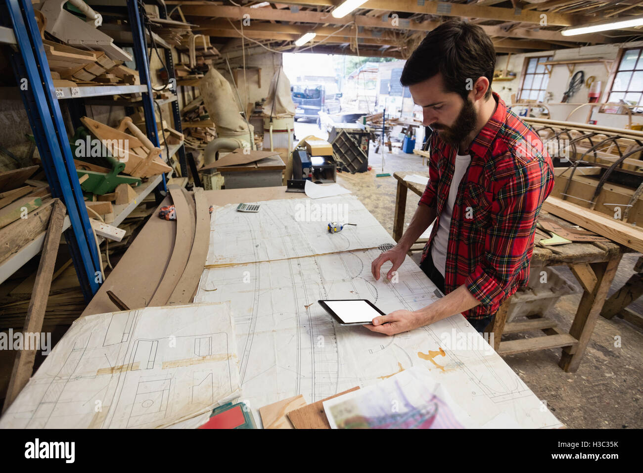 Man using digital tablet while looking at blueprint Stock Photo - Alamy