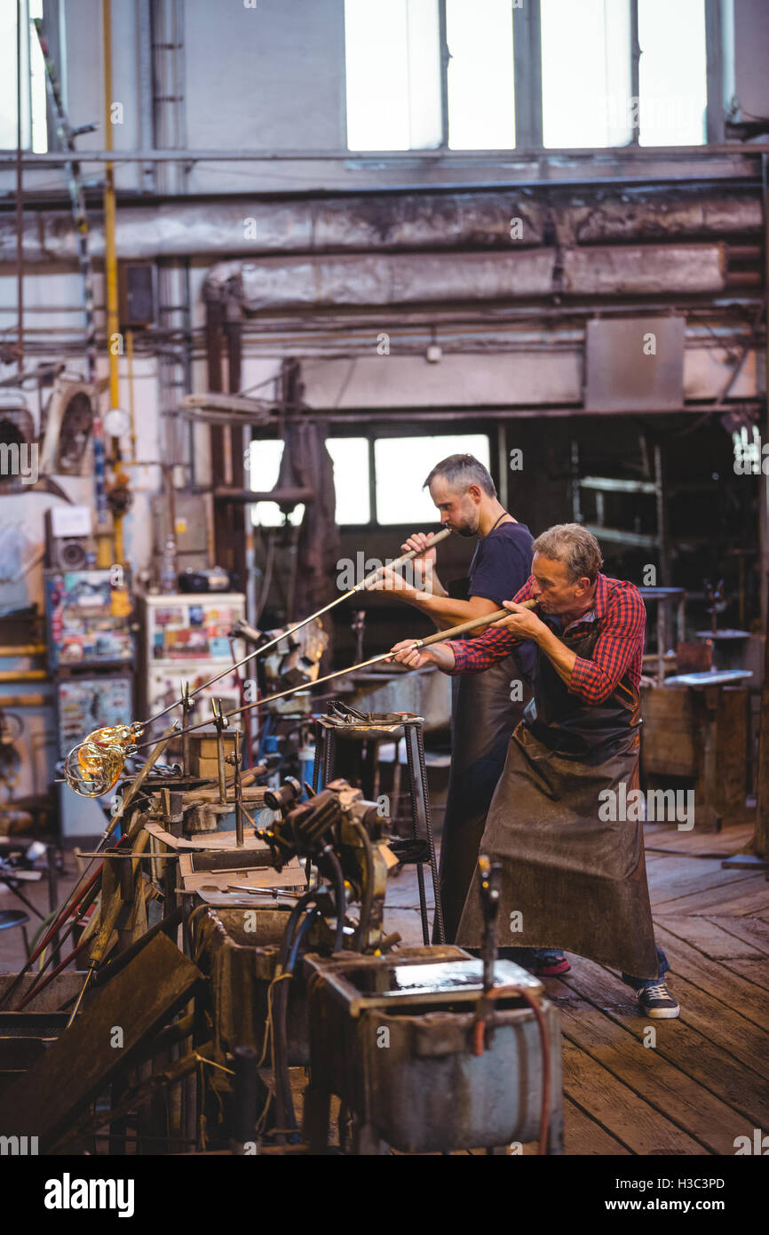 Glassblower shaping a glass on the blowpipe Stock Photo - Alamy