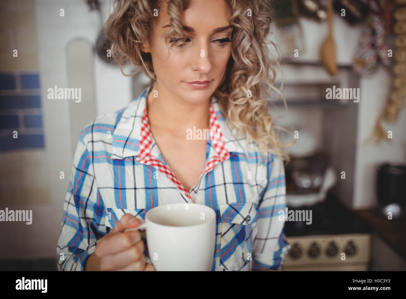 Beautiful woman having coffee in kitchen Stock Photo - Alamy