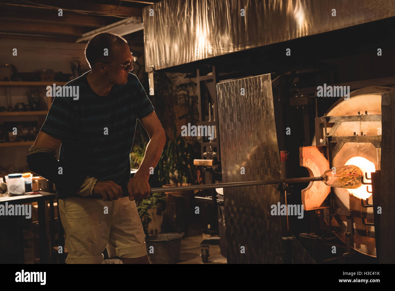 Glassblower heating a glass in furnace Stock Photo - Alamy