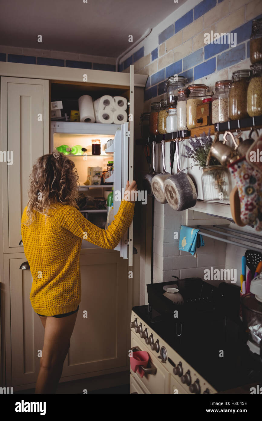 Woman looking for food in refrigerator in kitchen Stock Photo - Alamy
