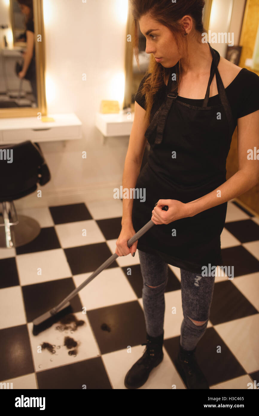Female hairdresser cleaning hair waste on floor Stock Photo - Alamy