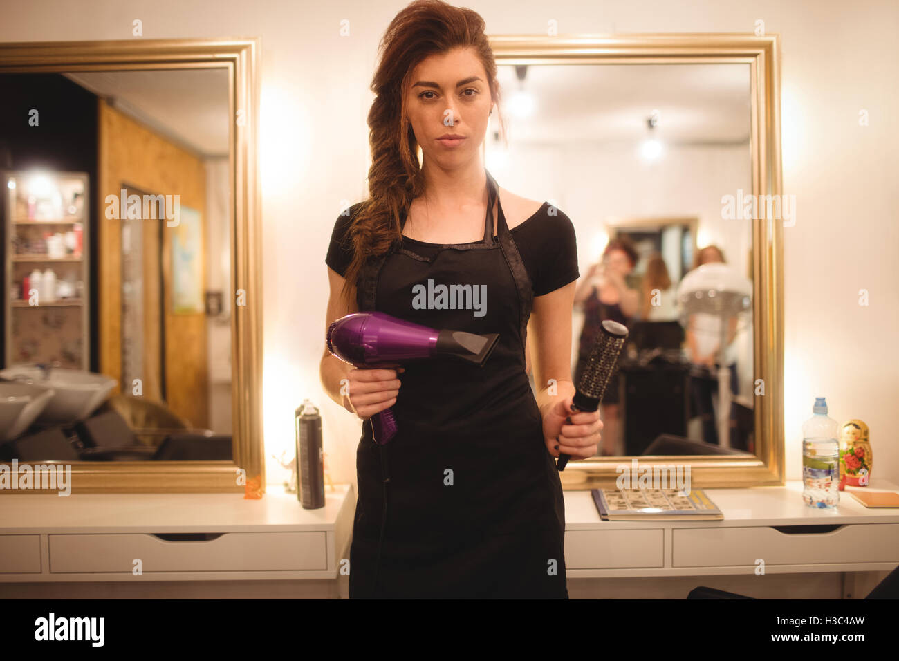 Female hairdresser holding hair dryer machine and hairbrush Stock Photo ...