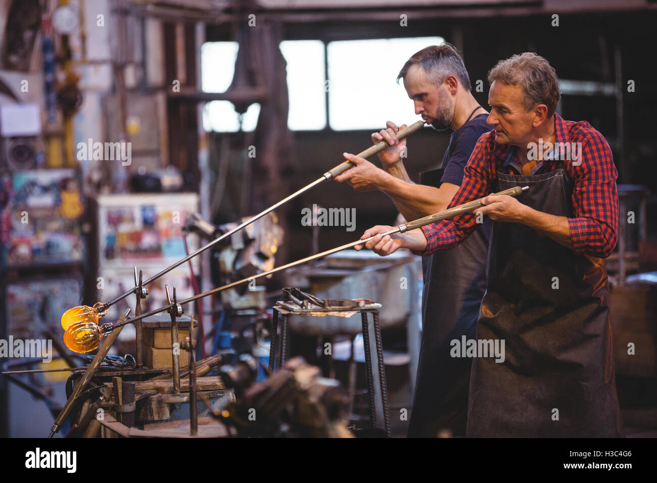 Glassblower shaping a glass on the blowpipe Stock Photo - Alamy