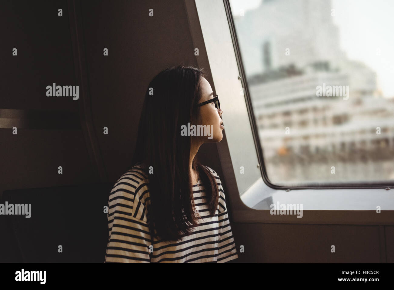 Young woman looking through window Stock Photo - Alamy