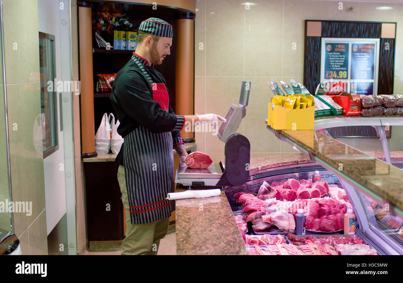 Butcher checking the weight of meat at counter Stock Photo - Alamy