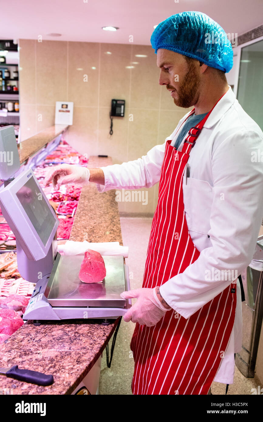 Butcher checking the weight of meat at counter Stock Photo - Alamy