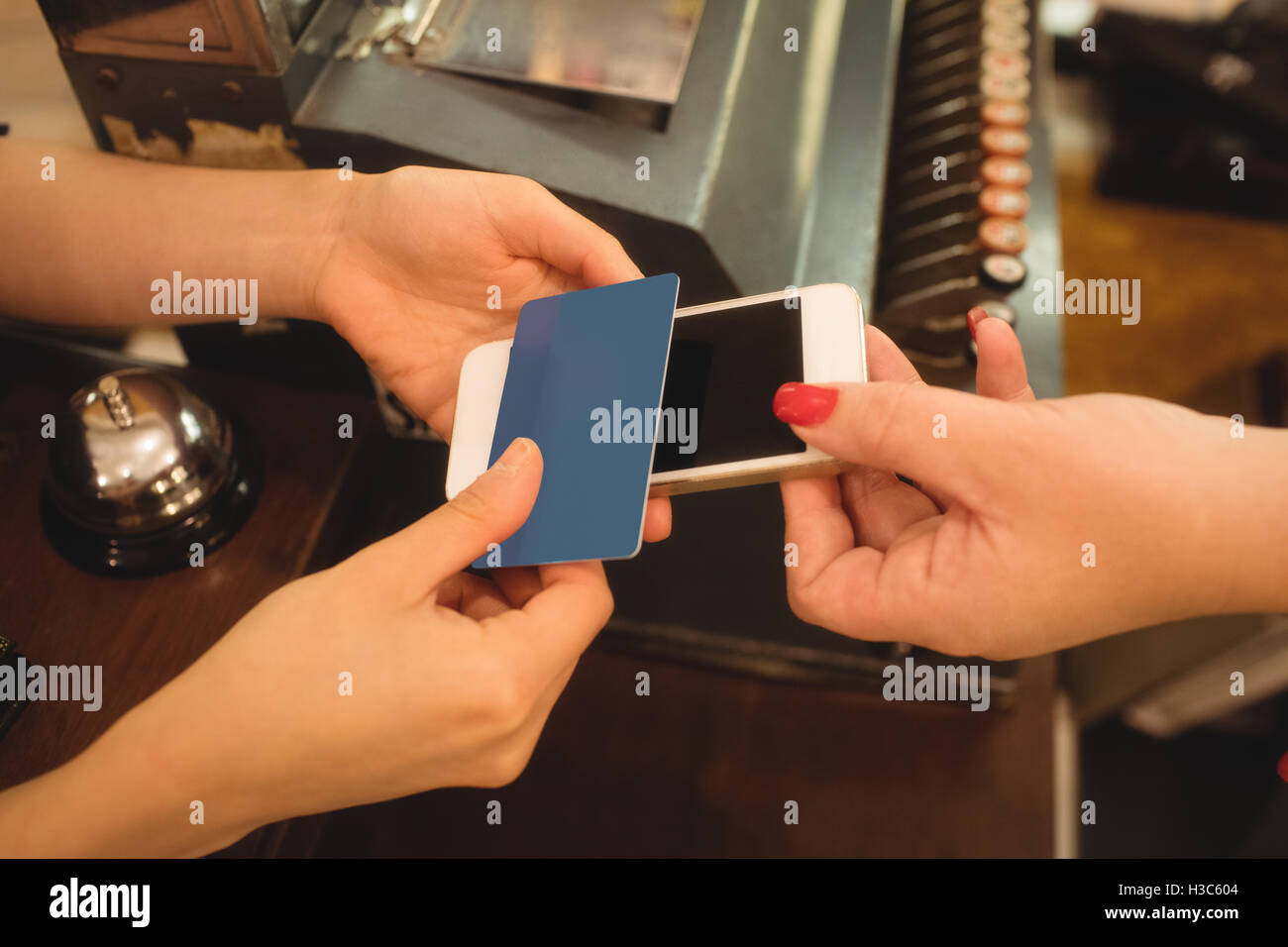 Customer giving her phone and credit card to cashier Stock Photo - Alamy