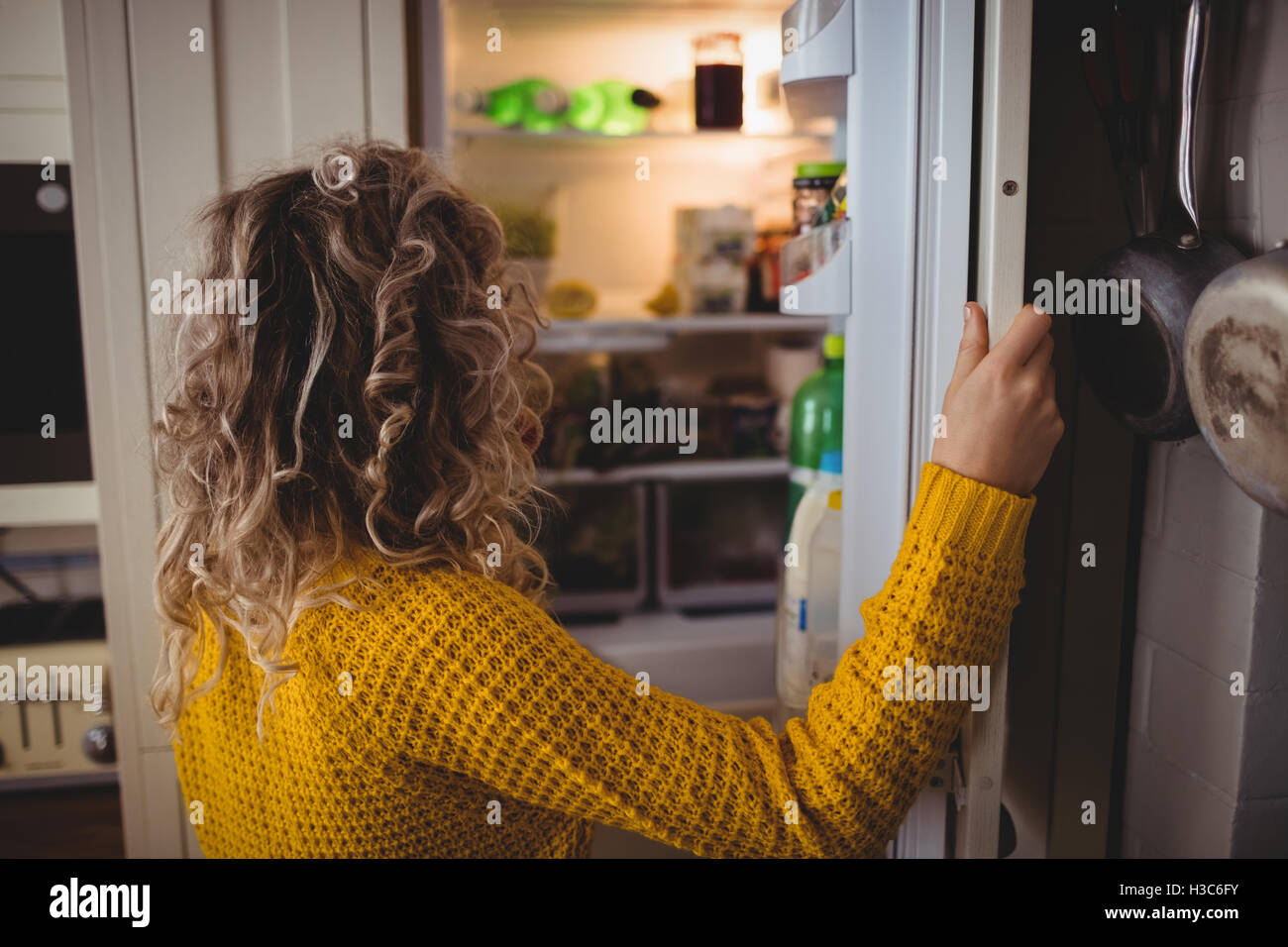 Woman looking for food in refrigerator in kitchen Stock Photo - Alamy