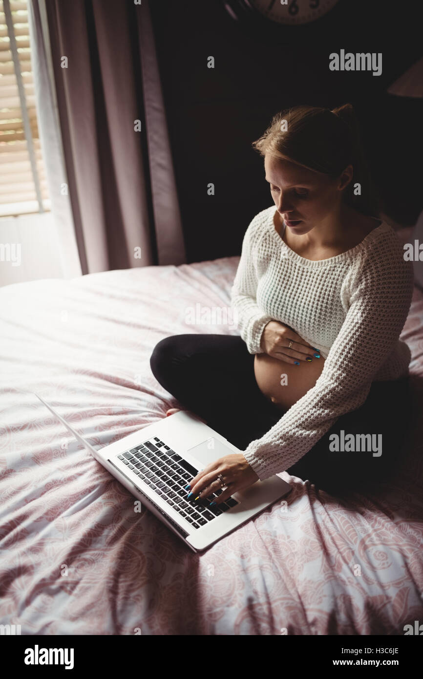 Pregnant woman using laptop in bedroom Stock Photo - Alamy