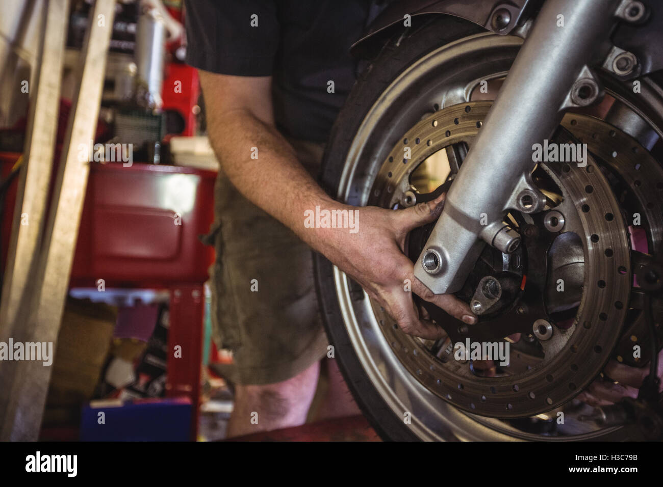 Mechanic examining a motorbike disc brake Stock Photo - Alamy