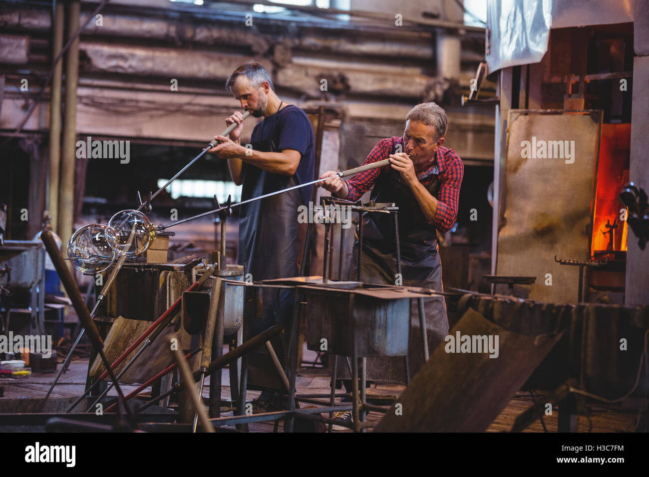 Glassblower shaping a glass on the blowpipe Stock Photo - Alamy