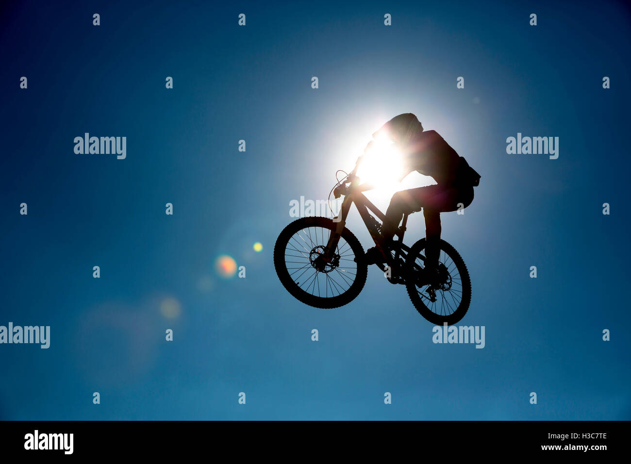 An extreme rider is making a free style jump from a ramp. The young boy ...