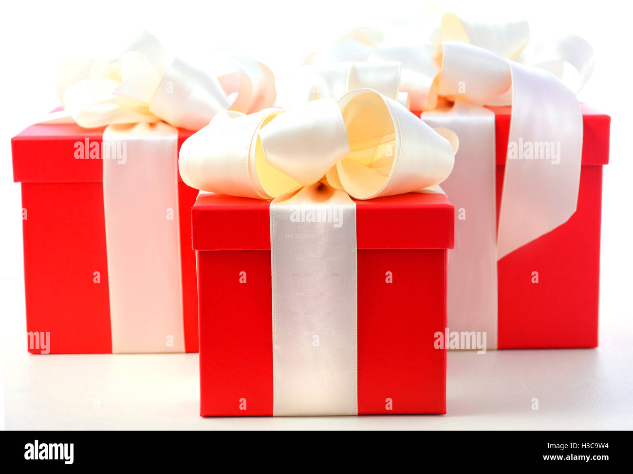 Bright red festive holiday gift boxes beautifully wrapped in cream ...