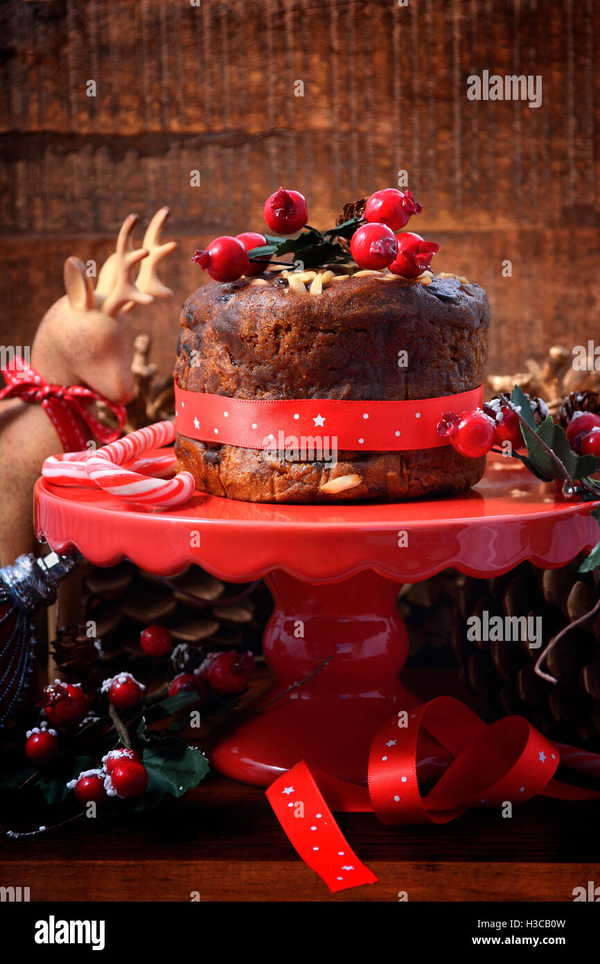 Festive Christmas small rich fruit cake on a red cake stand with ...