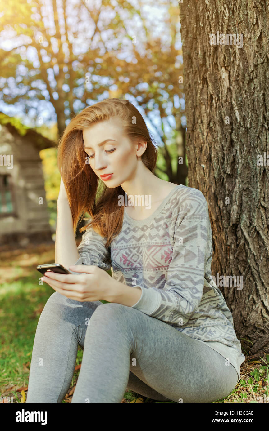 Beautiful girl looks on the phone Stock Photo - Alamy