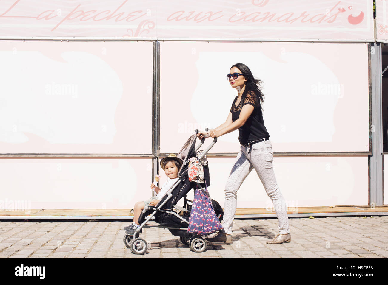 Mother pushing toddler son in stroller on sidewalk Stock Photo - Alamy