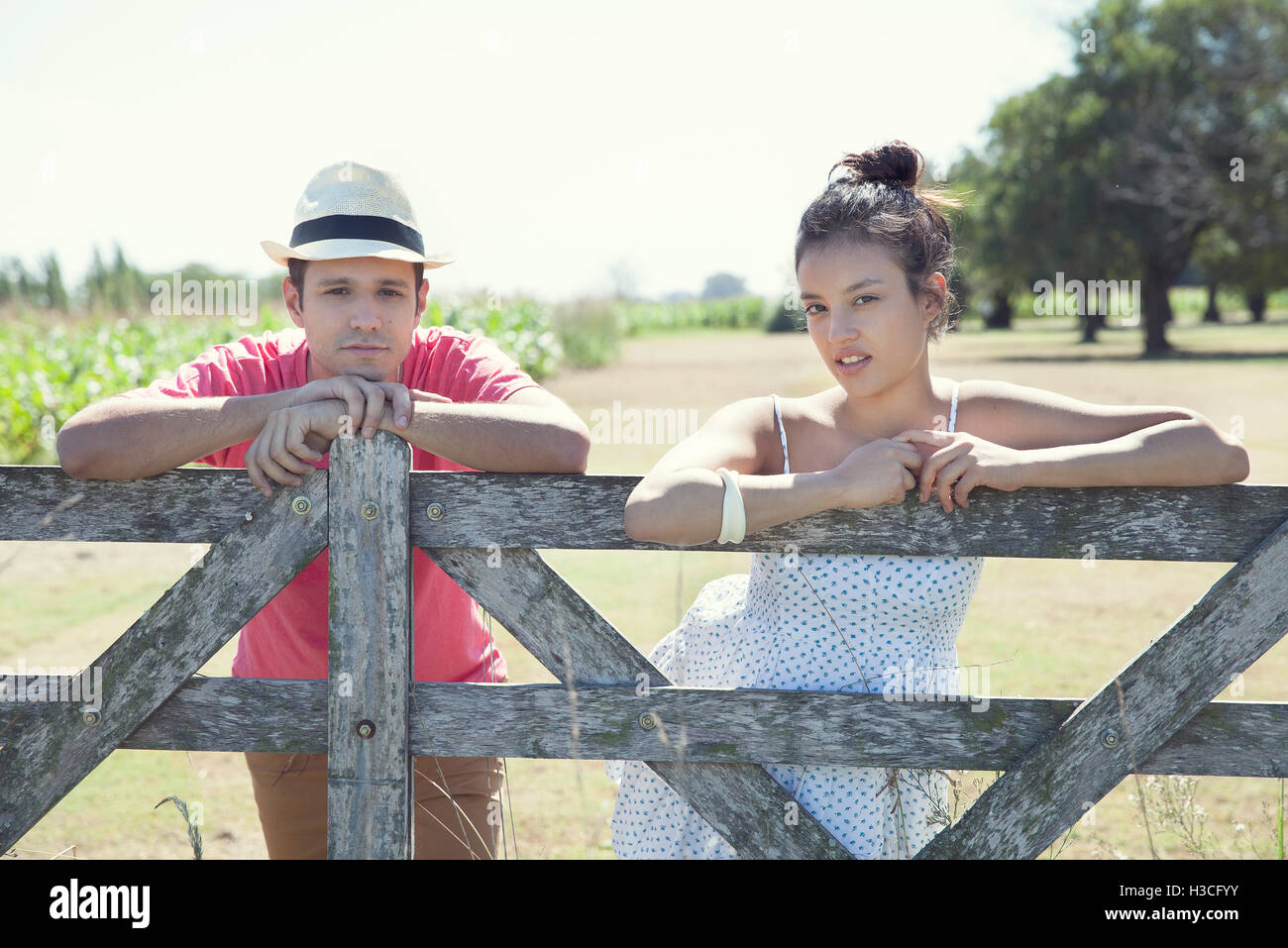 Couple learning against wooden fence, portrait Stock Photo - Alamy